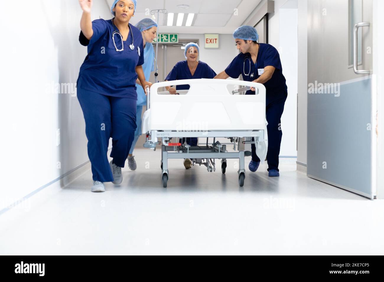 Diverse group of healthcare workers pushing patient in bed down ...