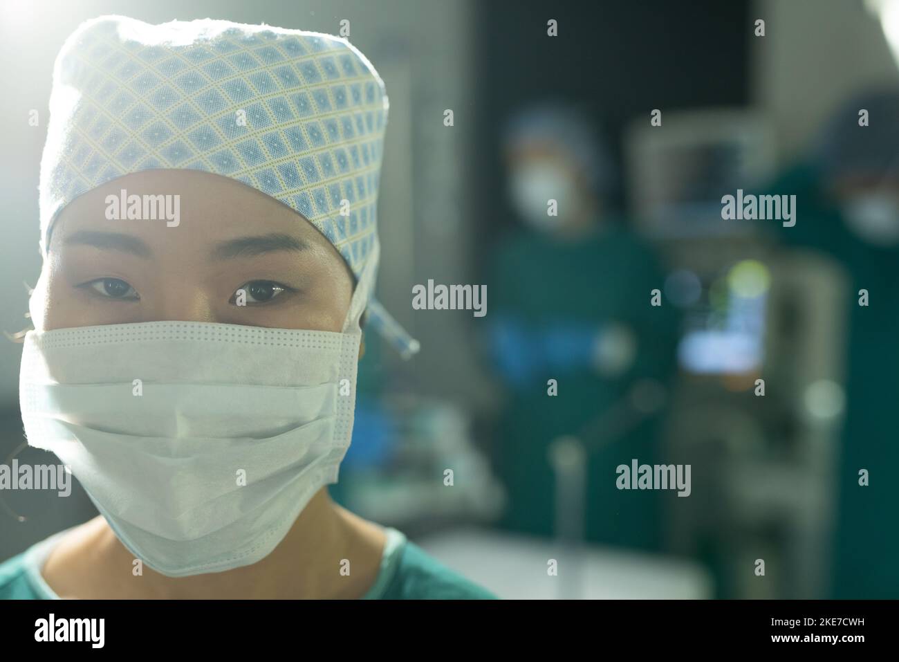 Portrait of asian female surgeon in surgical cap and mask in operating ...