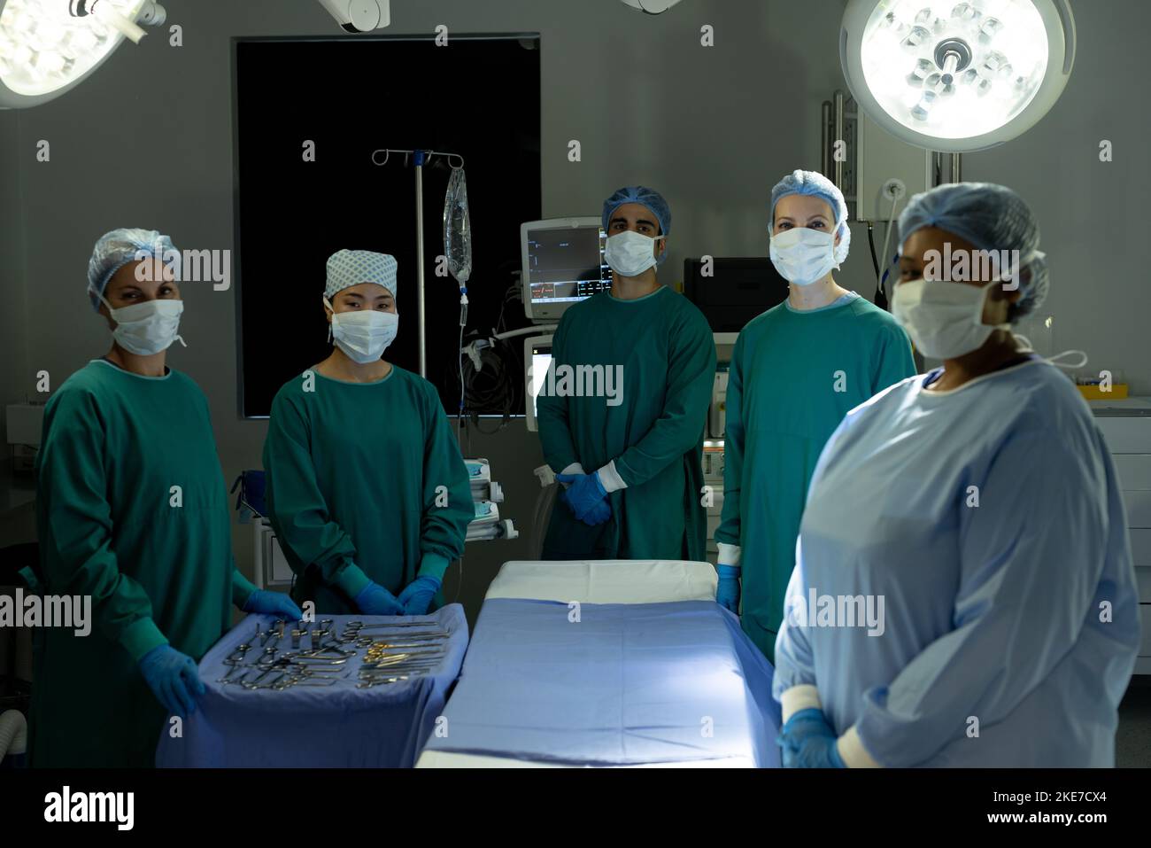 Diverse team of surgeons and techs ready for operation, standing around ...