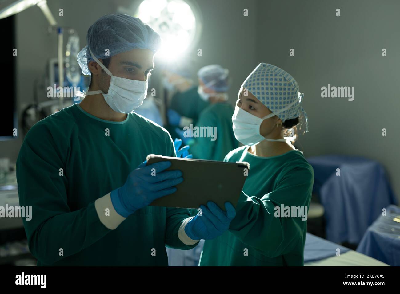 Diverse female and male surgeon in discussion, using tablet in ...