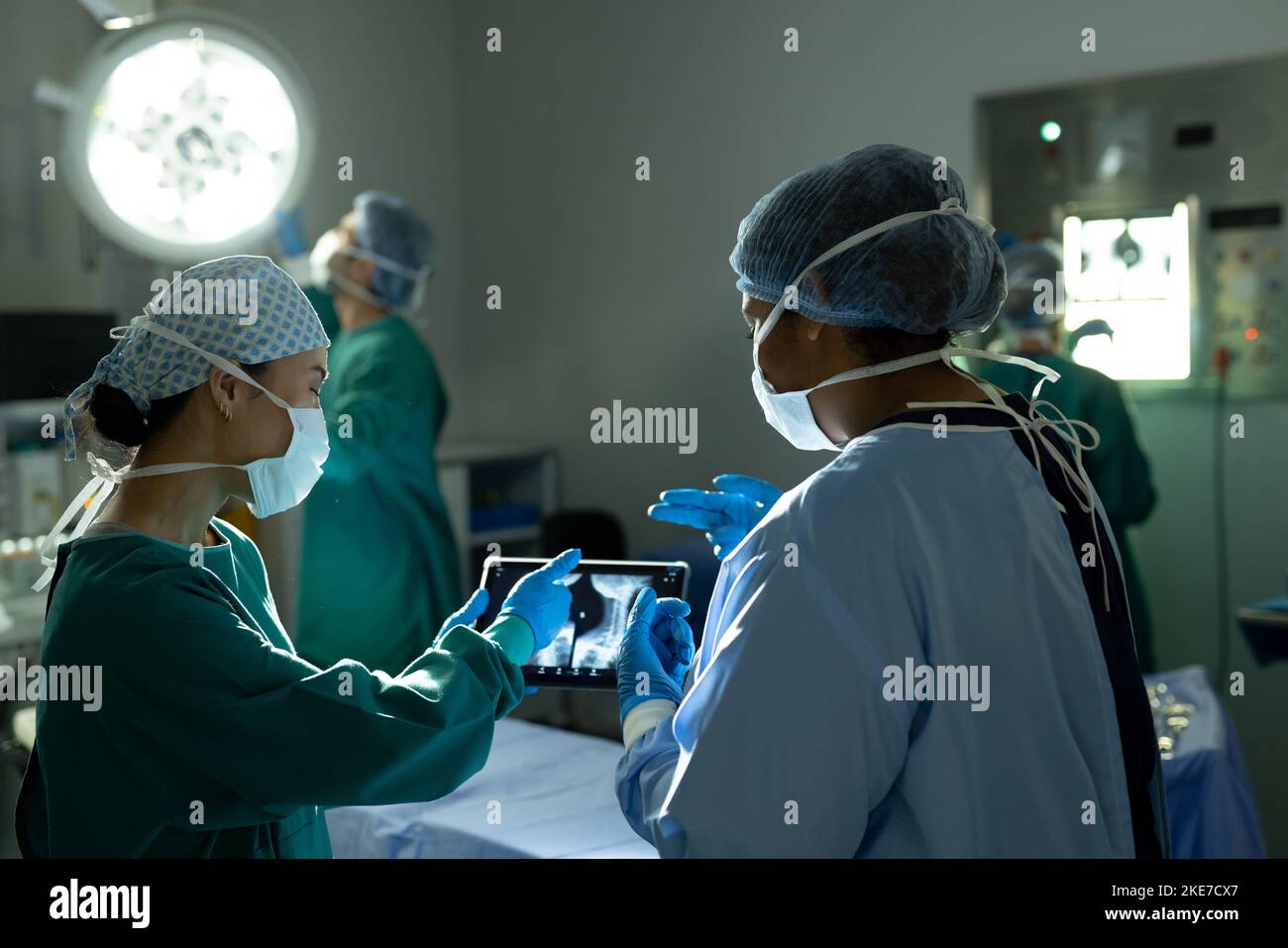 Two diverse female surgeons preparing for operation, studying x-ray on ...