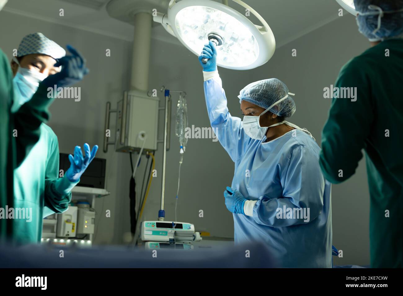 Biracial female surgical tech adjusting light in operating theatre ...