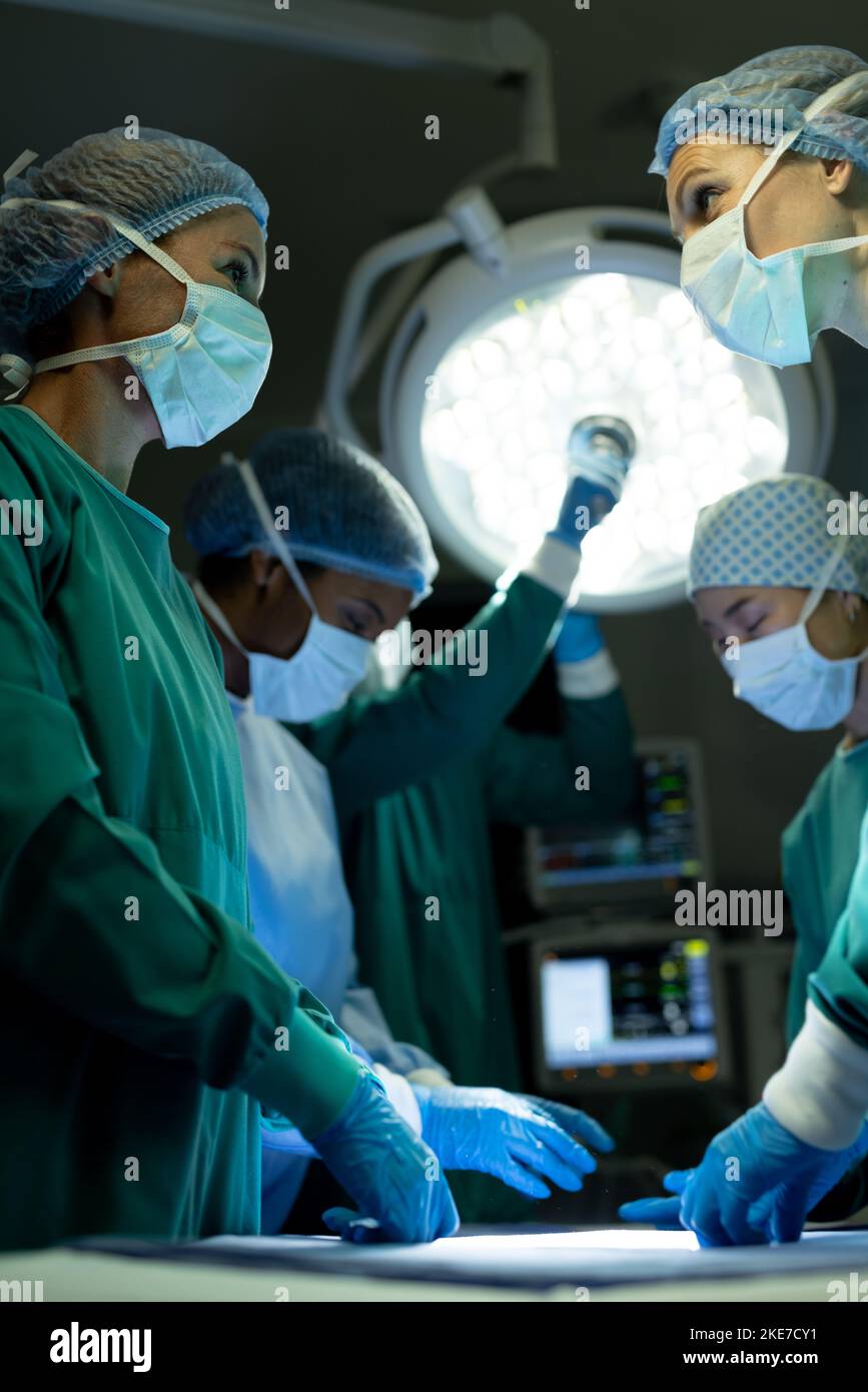 Vertical of diverse female surgeons in discussion in operating theatre ...