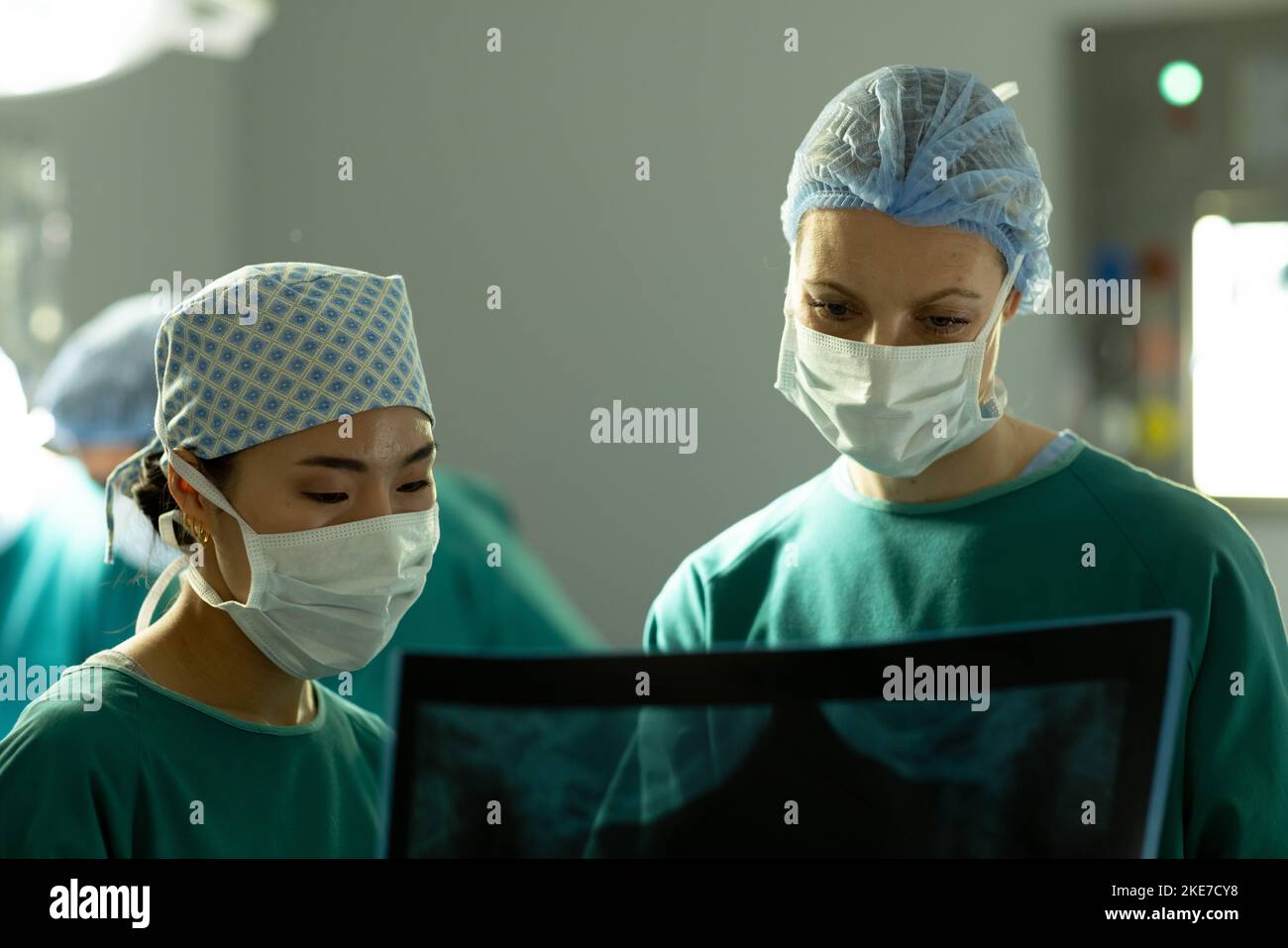 Two diverse female surgeons studying x-ray in operating theatre during ...