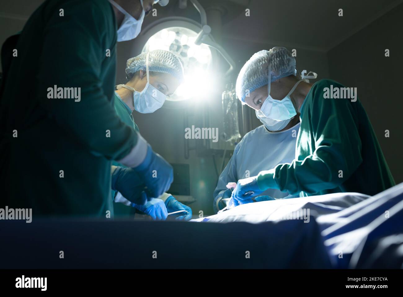 Diverse group of female and male surgeons operating on patient in ...