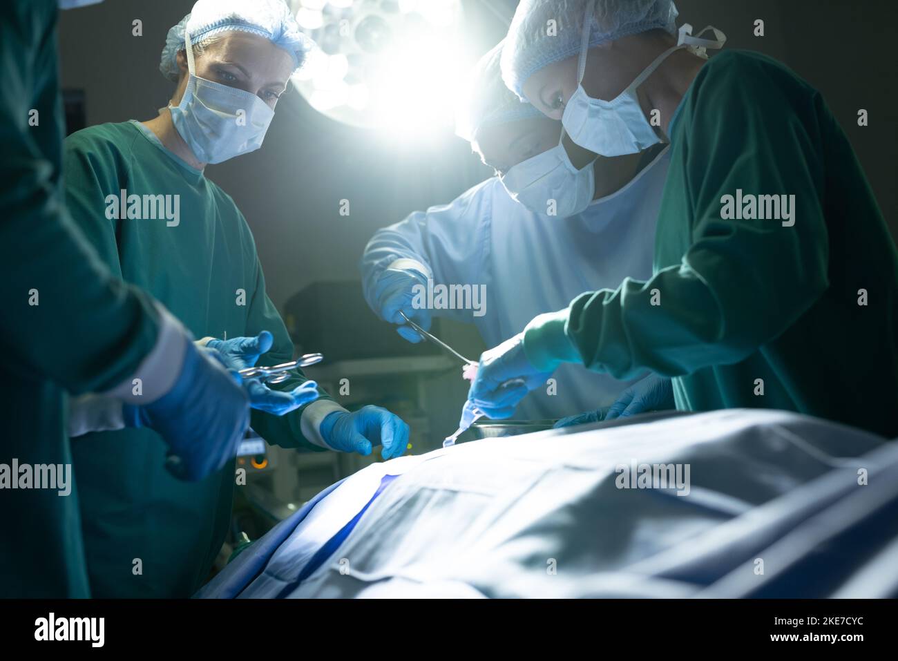 Diverse group of female and male surgeons operating on patient in ...