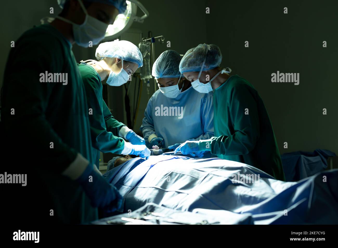 Diverse group of female surgeons and male tech operating on patient in ...