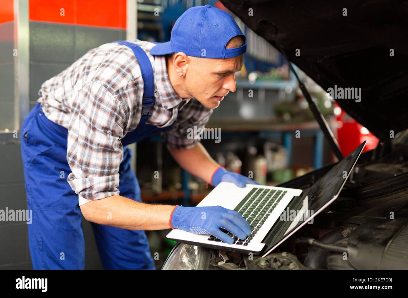Mechanic with laptop near car engine in auto service Stock Photo - Alamy