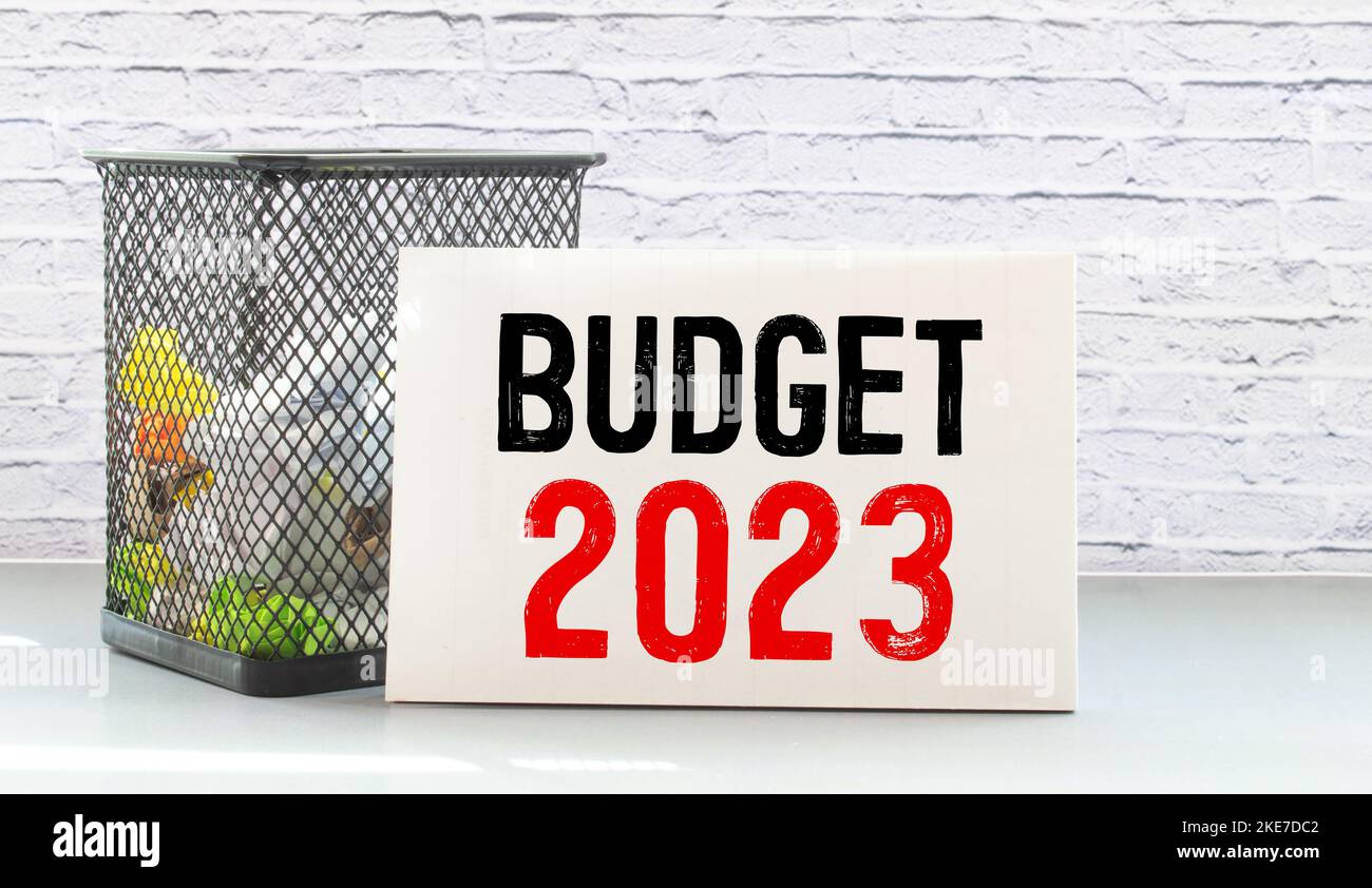 Notepad with text BUDGET 2023, glasses, paper clips, white calculator ...