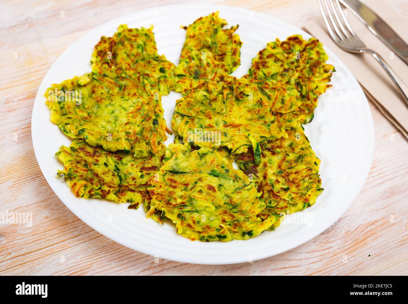 Top view of zucchini pancakes with white sauce at white plate on table ...