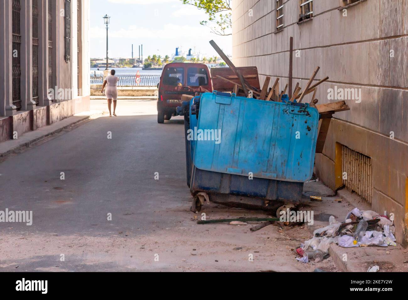Garbage pile on a dirty sidewalk. The city garbage containers are full ...