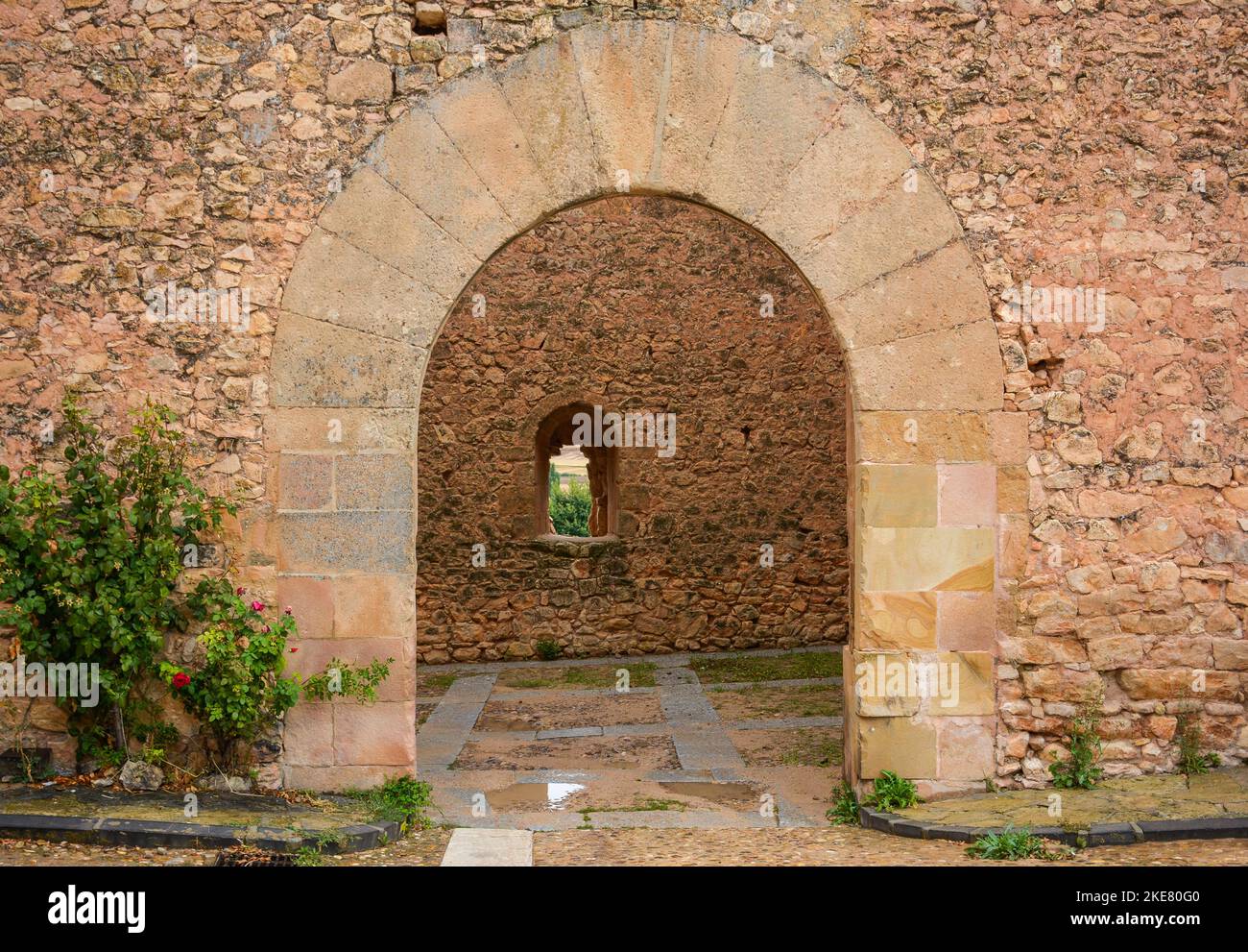 An arch gate in old stony wall inside historic building in the Spanish ...
