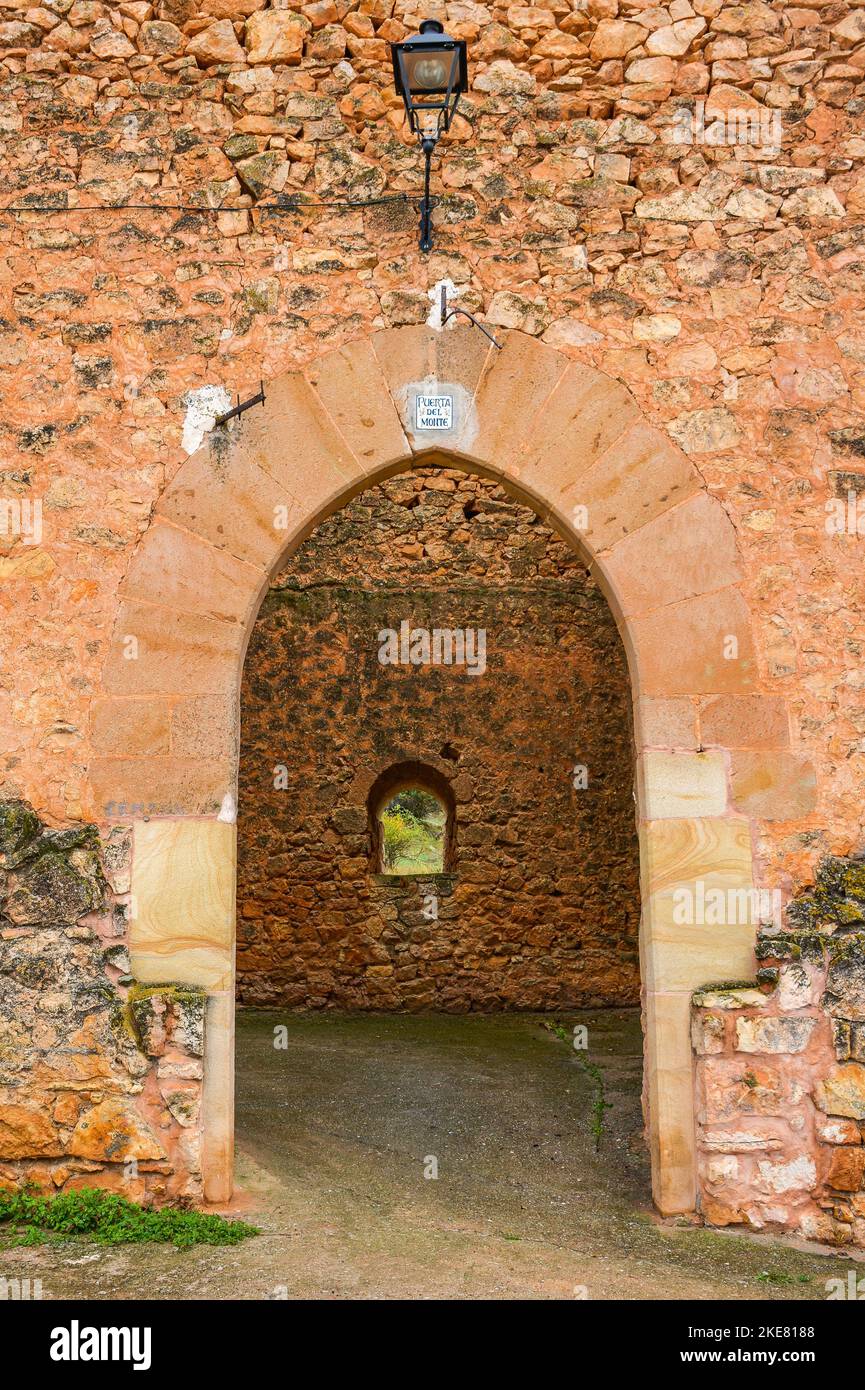 An arch gate with lamp over it in old stony wall inside historic ...