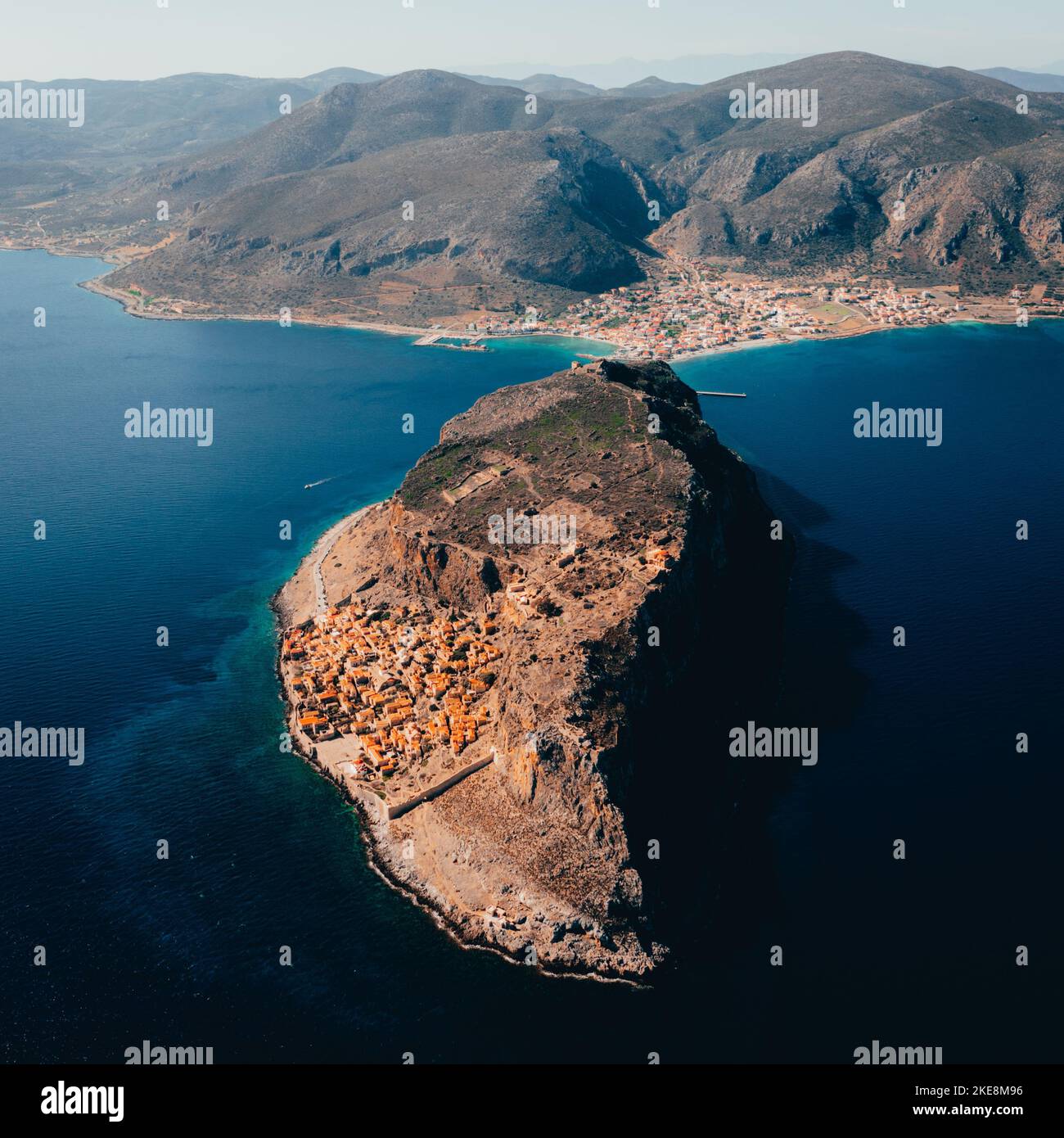 A high angle of the island village buildings with the blue sea below in ...