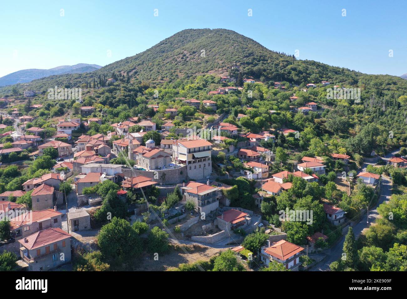 The red roof houses on a forested mountain against the clear sky in ...