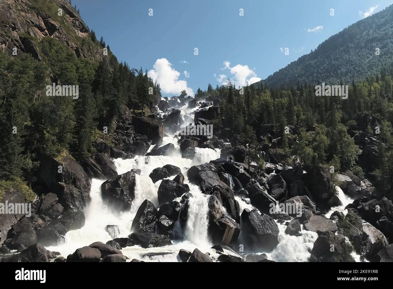 The Uchar Falls flowing down the rocks surrounded by lush larch trees ...