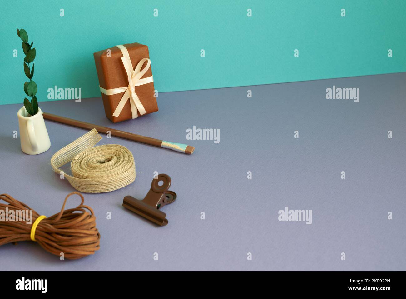 Gift box, ribbon roll, plant on purple table. blue background Stock ...