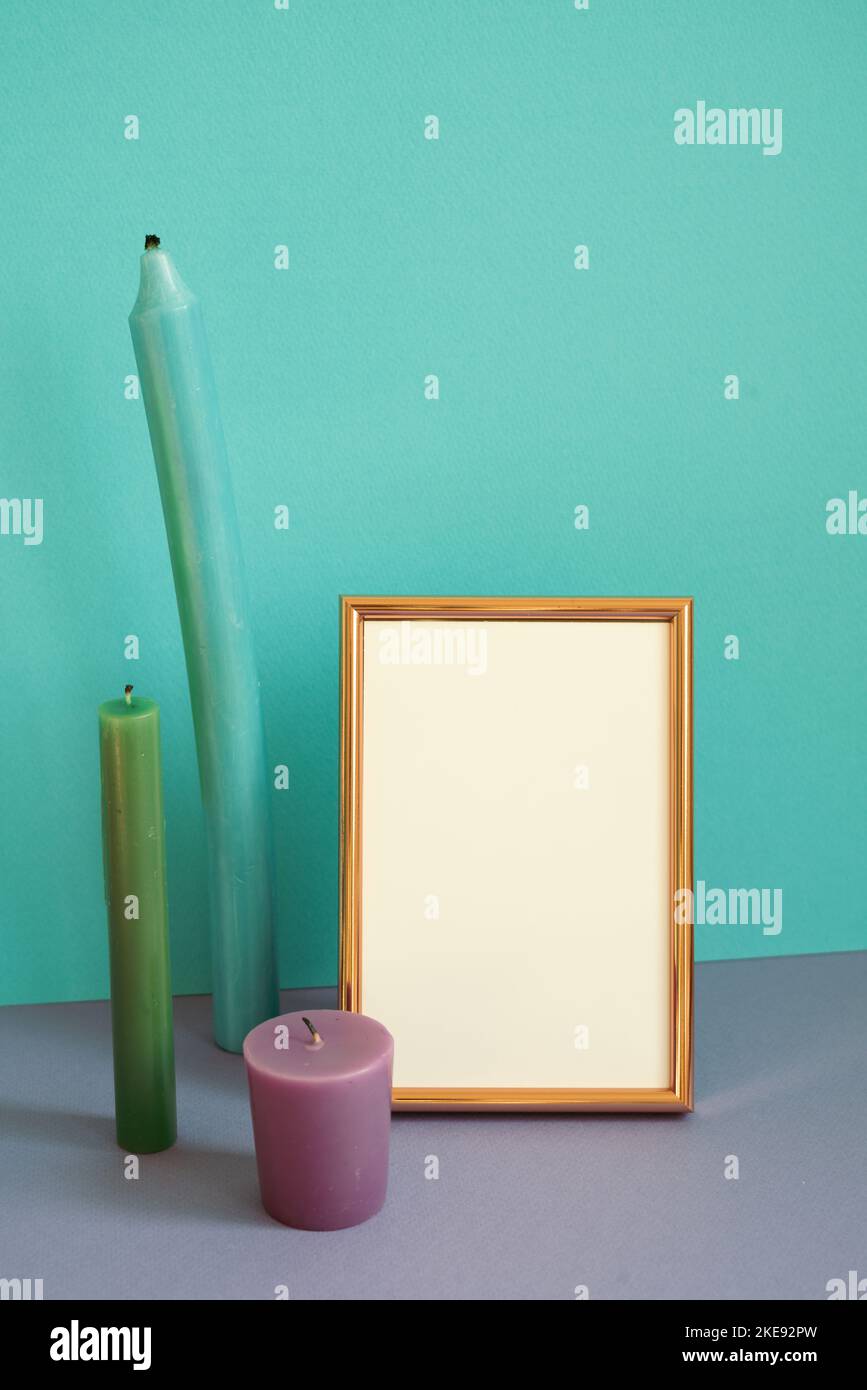 Picture frame and colorful candles on purple table. blue wall ...