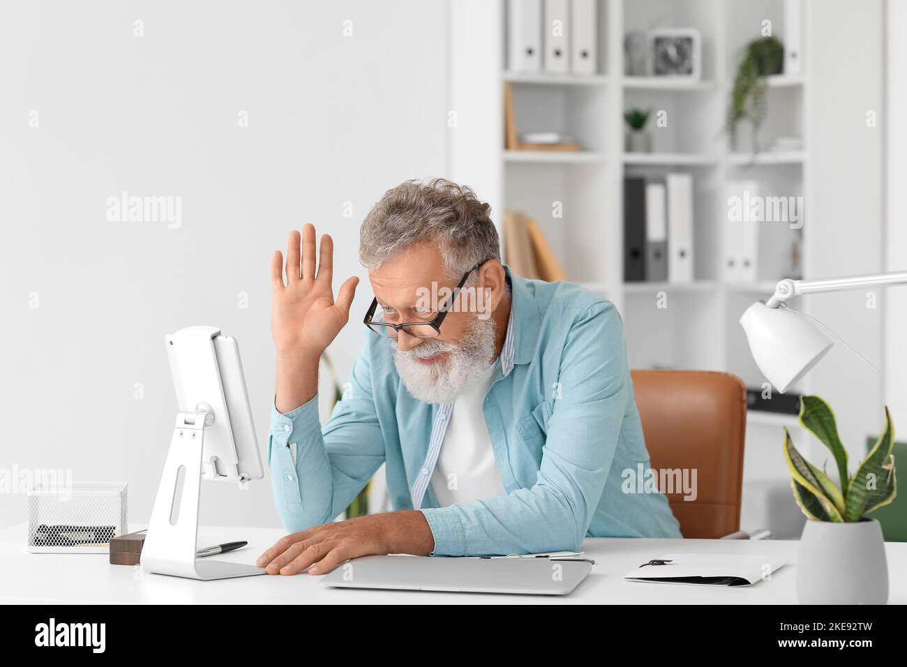 Senior man video chatting with tablet computer at table in office Stock ...