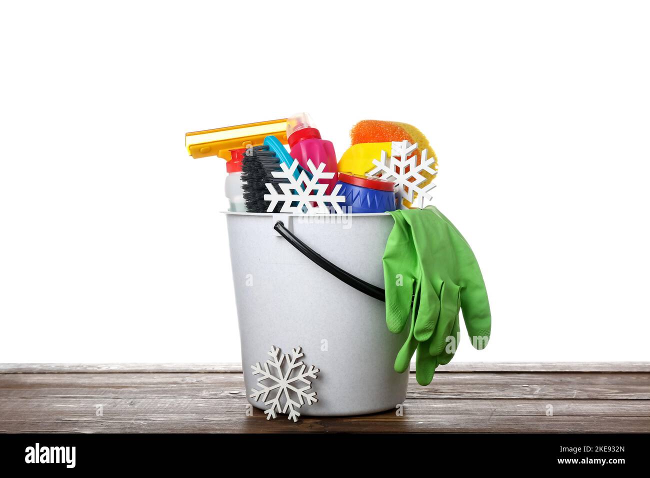 Bucket with cleaning supplies and snowflakes on table against white ...