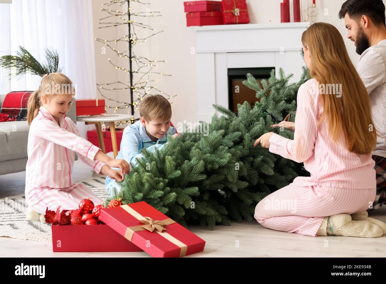 Happy parents and their little children with Christmas tree at home ...
