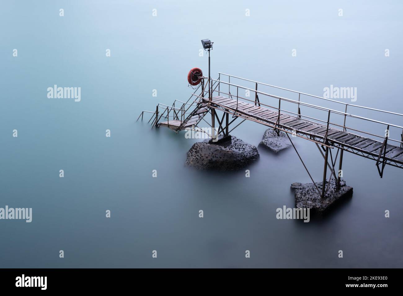 Short metal and wooden pier with steps leading into the sea. Long ...