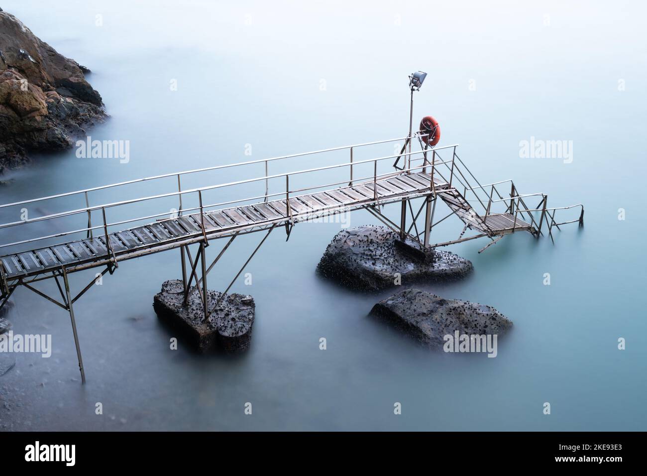 Short metal and wooden pier with steps leading into the sea. Long ...