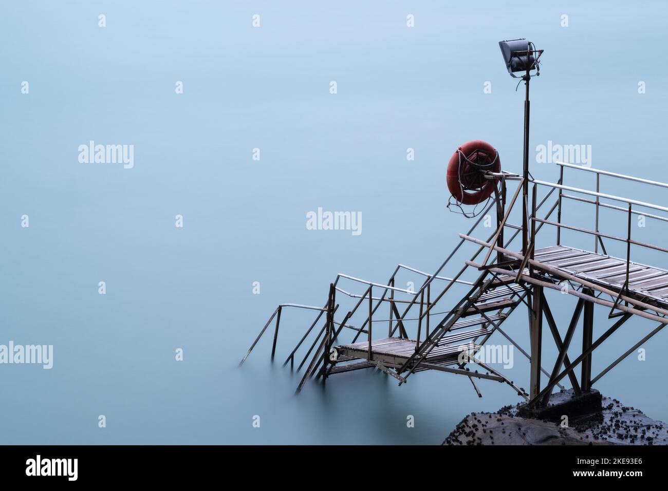 Short metal and wooden pier with steps leading into the sea. Long ...