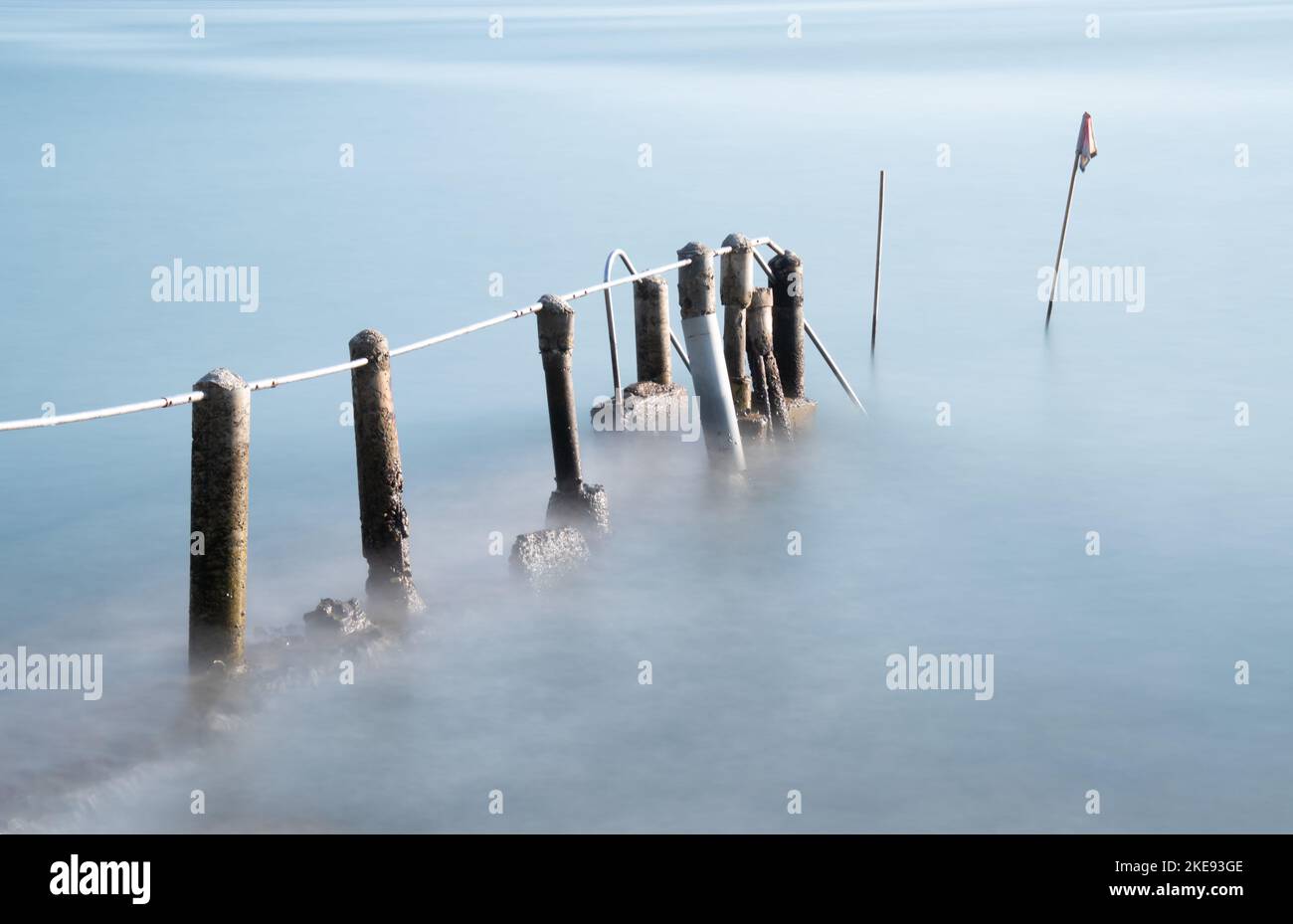 Old broken pier leads into the sea from a beach. The posts and rails ...