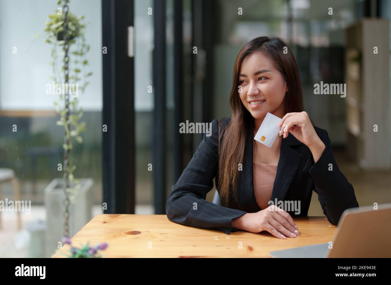 Portrait of a young Asian woman in a suit using credit card and ...