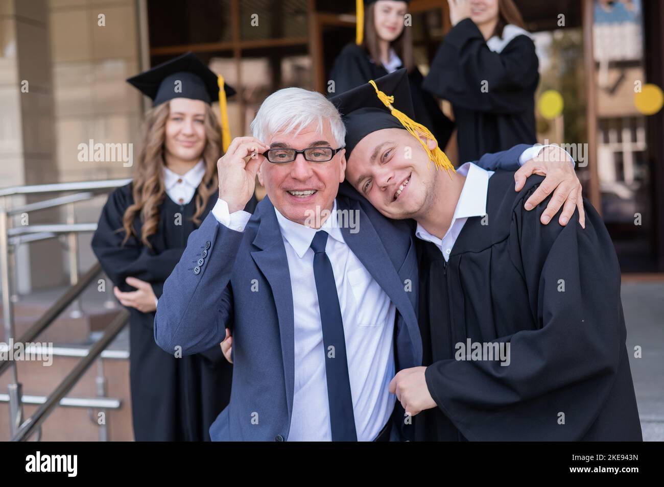 Father and son embrace at graduation. Parent congratulates university ...