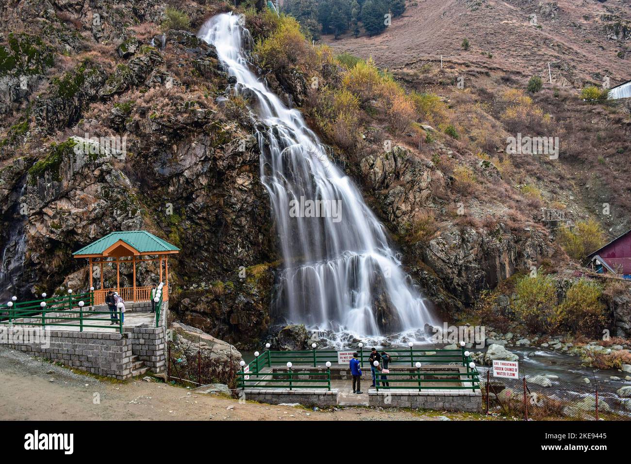 Visitors explore the waterfall during a cold autumn day in Drang about ...