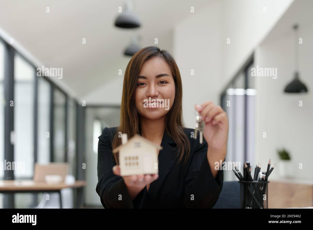 Portrait of an Asian female bank employee handing over a house and keys ...