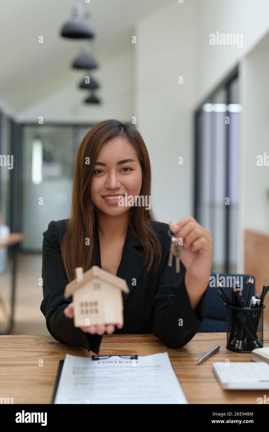 Portrait of an Asian female bank employee handing over a house and keys ... Portrait of an Asian female bank employee handing over a house and keys ...