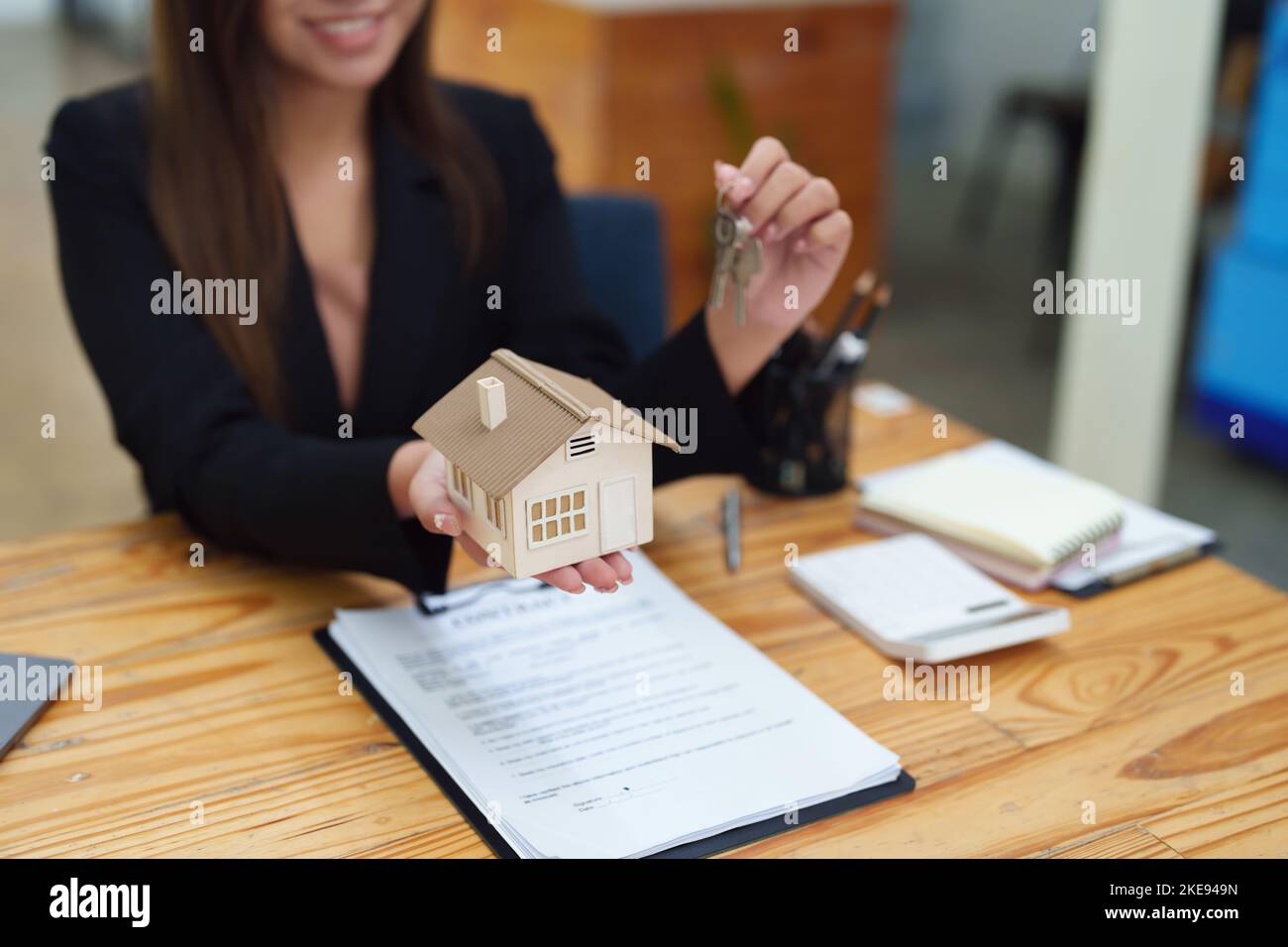Asian female bank employee handing over a house and keys to a client ...