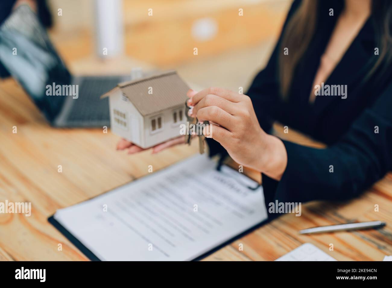 Asian female bank employee handing over a house and keys to a client ...