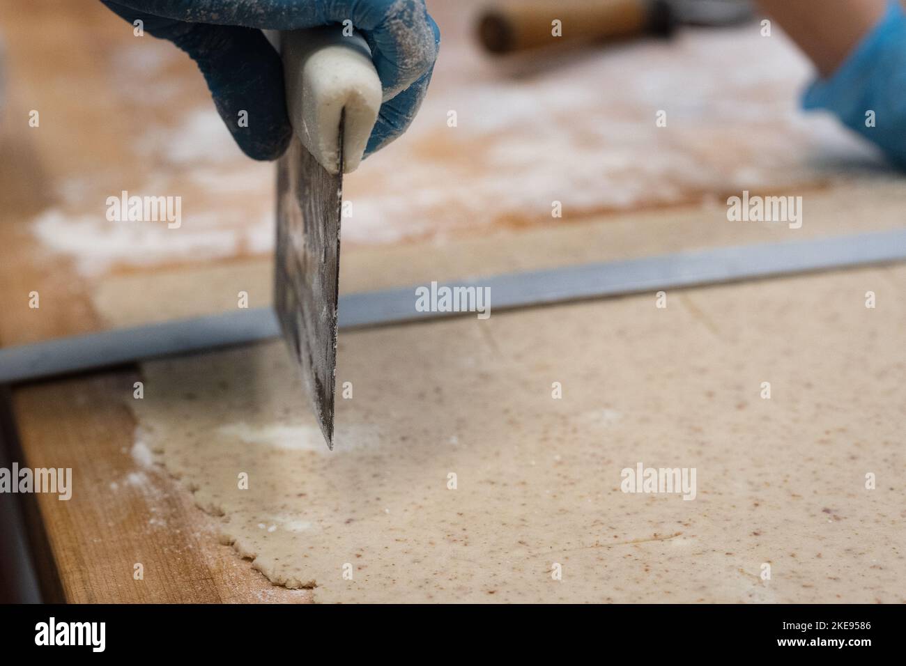 A baker scores the dough into its proper sizes for pastry making Stock ...