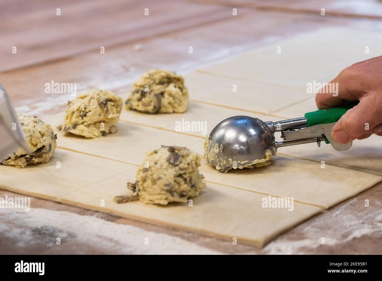 A baker scoops out a savory filling onto pastry dough Stock Photo - Alamy