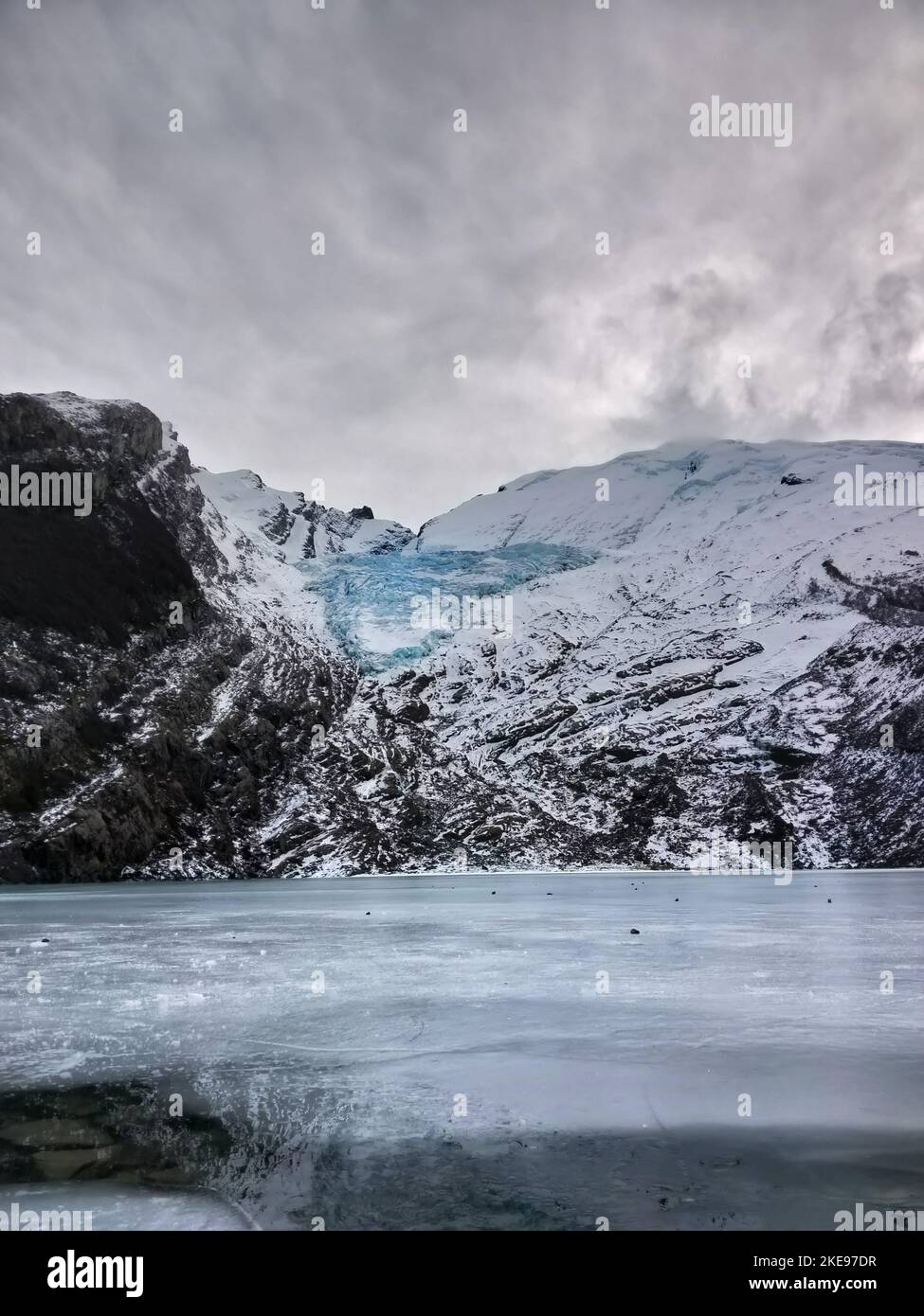 A vertical shot of a frozen lake in a snowy mountainous area on a ...