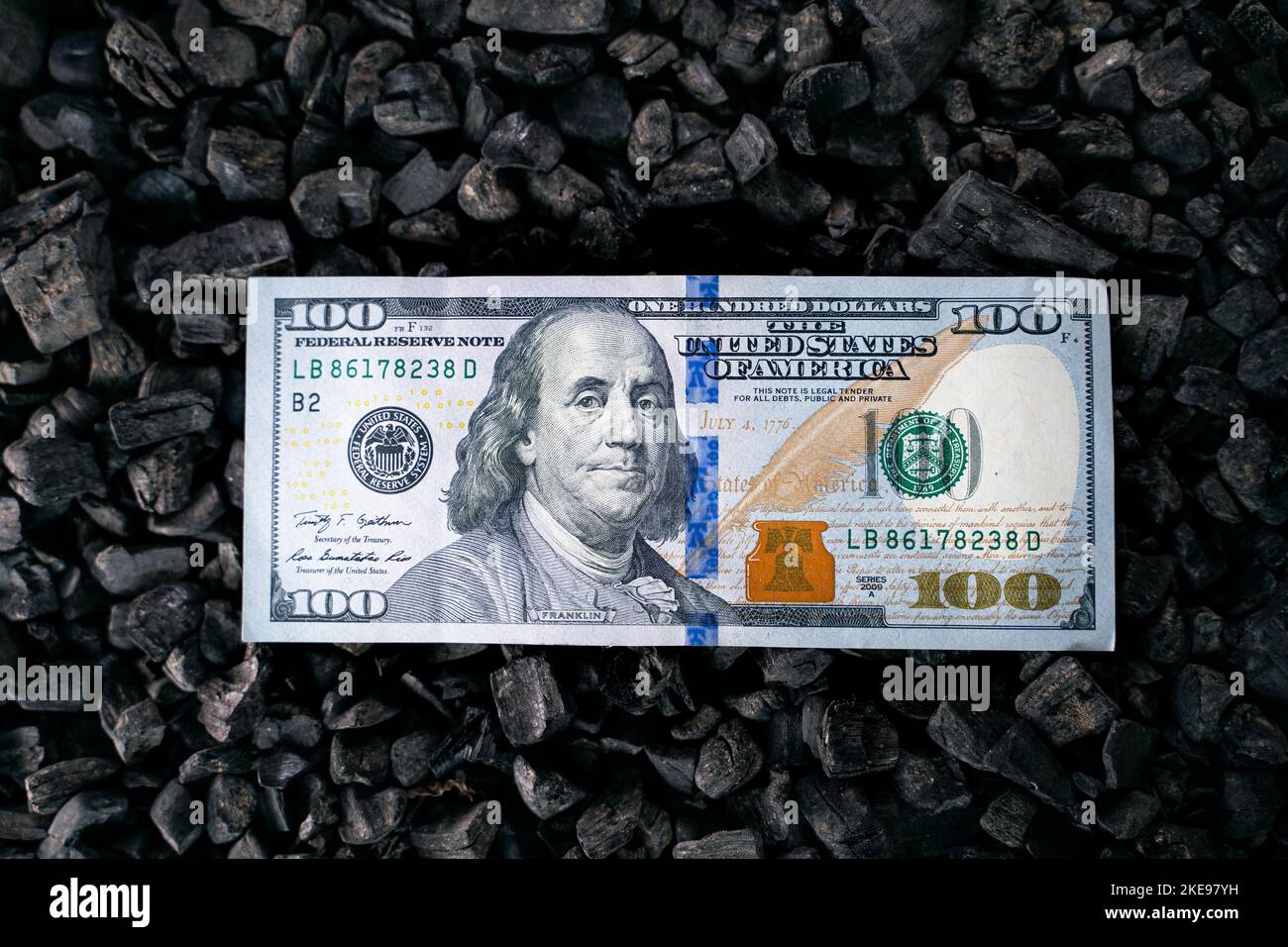 A hundred dollar bill lies on a black coal close-up, top view. Payment ...