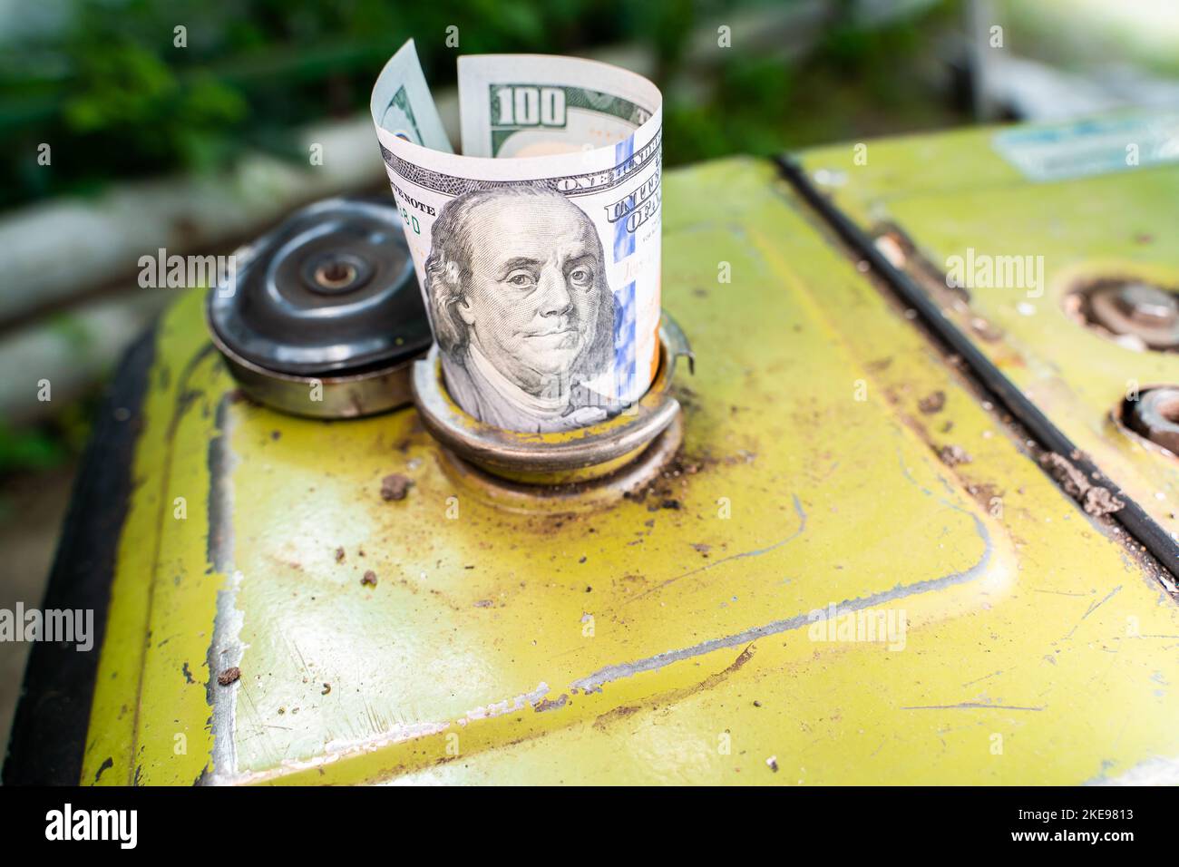 One hundred us dollars in the filler neck of a gas tank close-up on a ...
