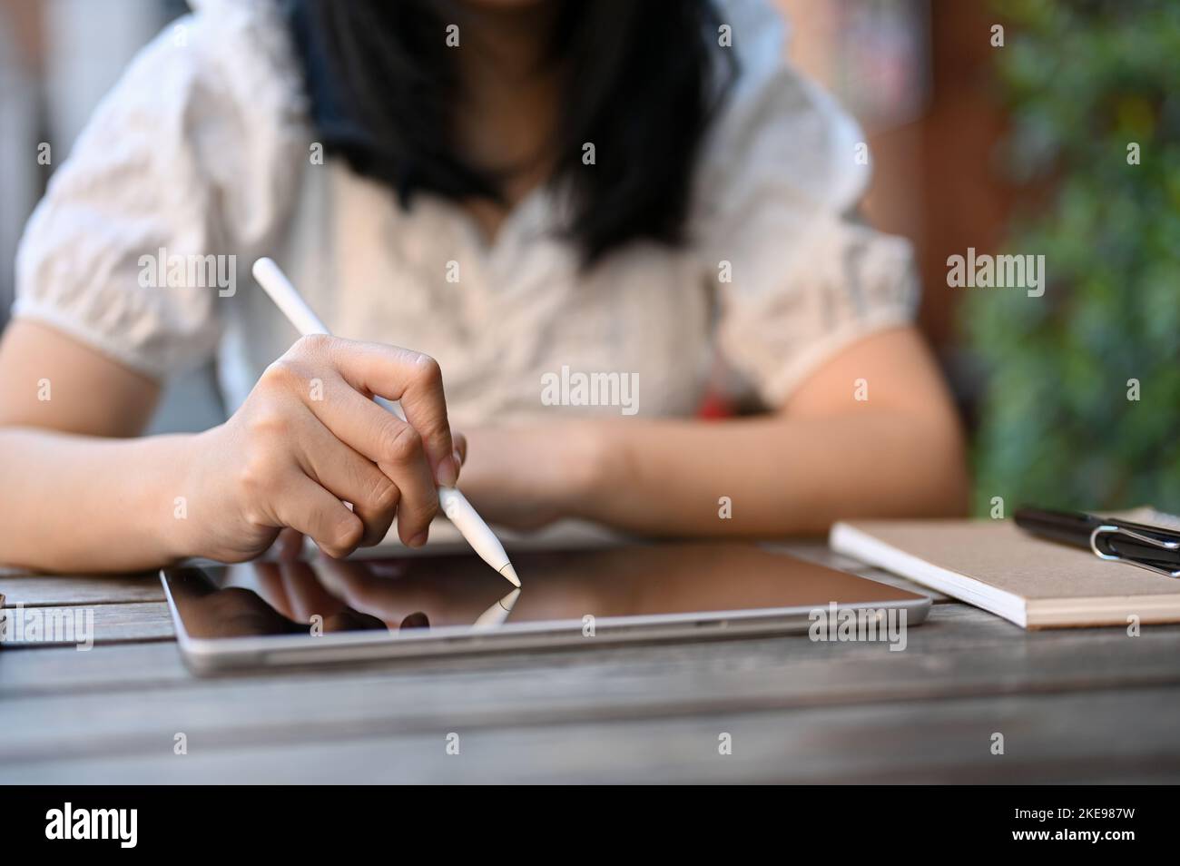 Asian female using stylus pen drawing on her digital tablet while ...