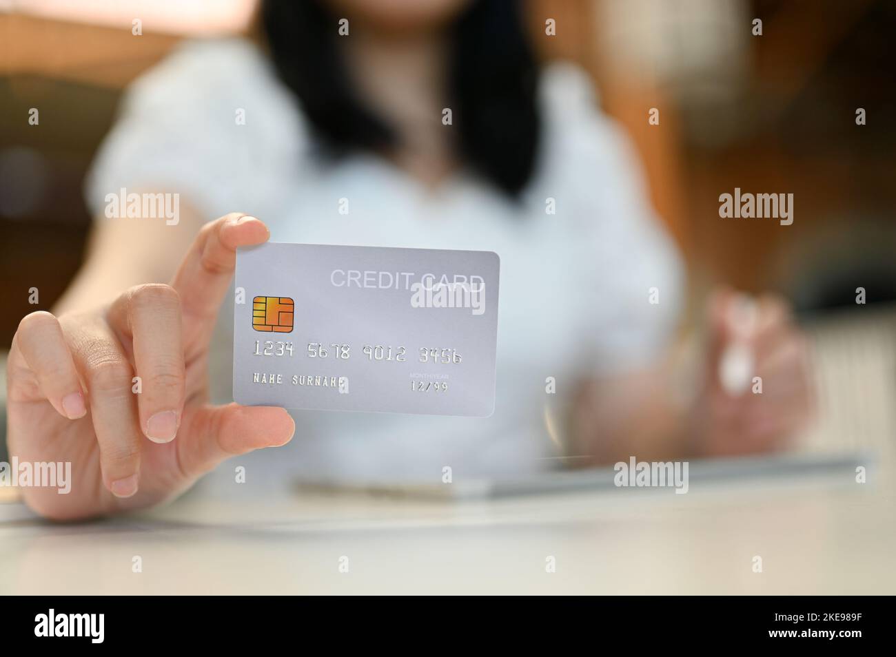 cropped shot, A female hand holding a silver credit card over blurred ...