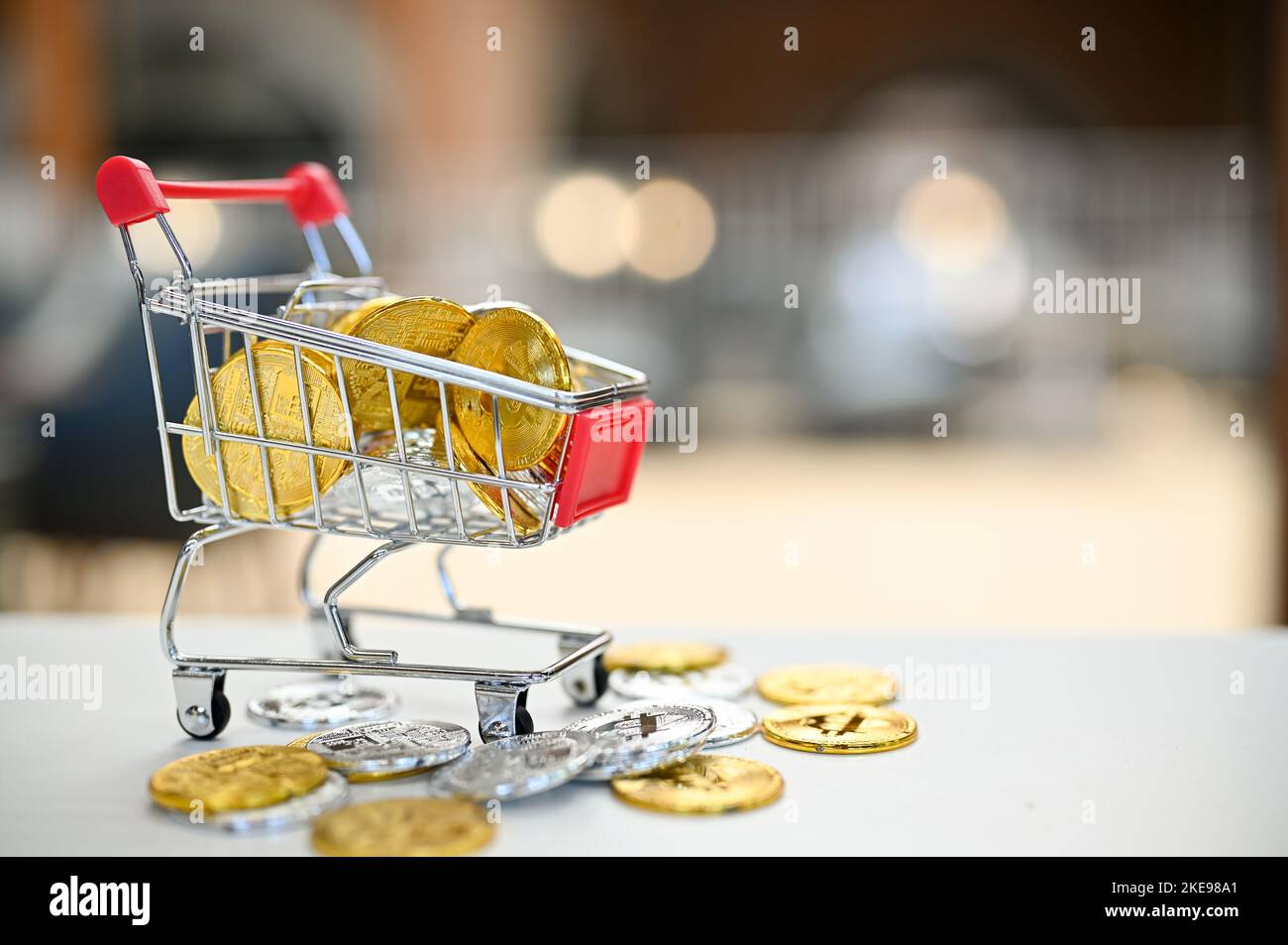 Silver and golden bitcoins in shopping cart on the table. Shopping, e ...