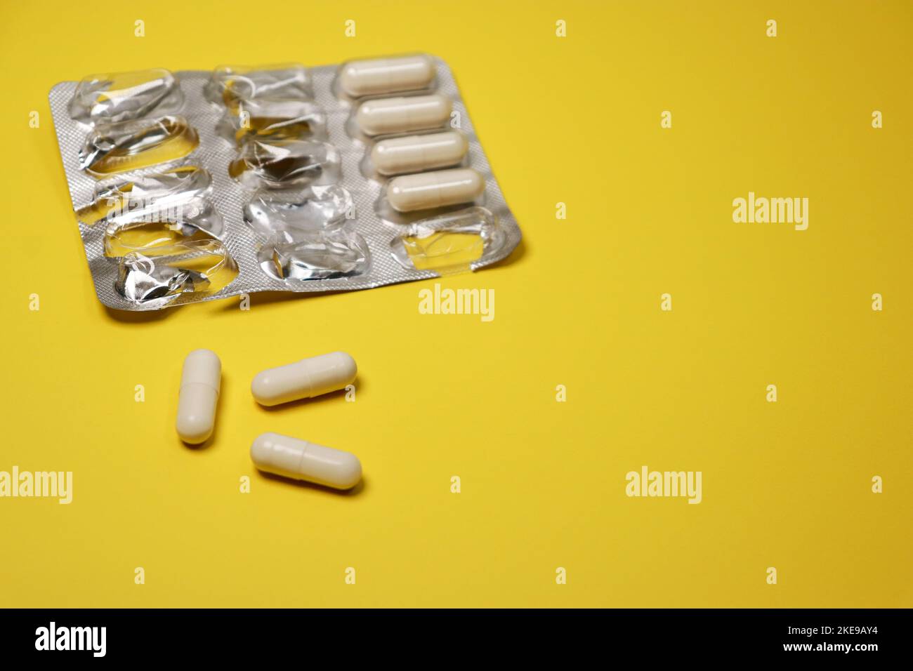 white capsules and pill pack on yellow background Stock Photo - Alamy