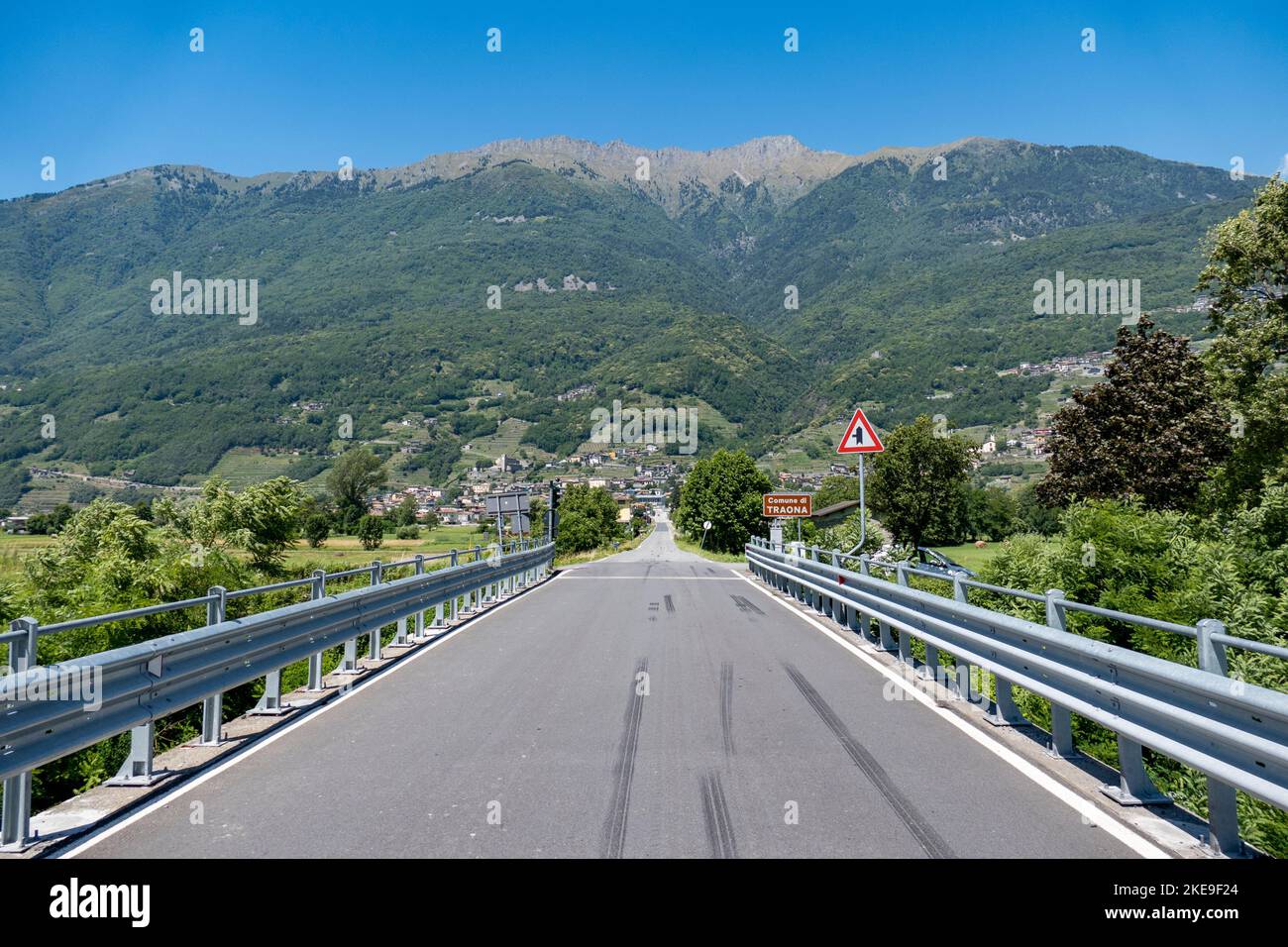 A narrow pavement in the countryside with hills and mountains in the ...