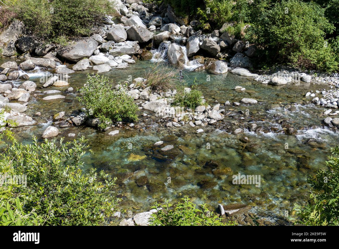 A small water body surrounded by stones and trees Stock Photo - Alamy