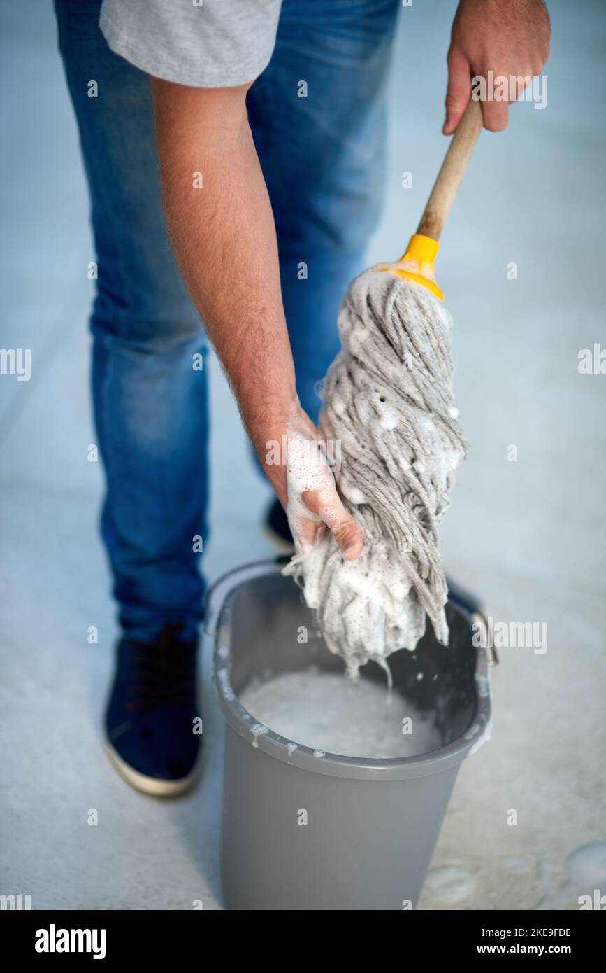 Ringing it out. an unrecognizable man ringing out a mop while cleaning ...