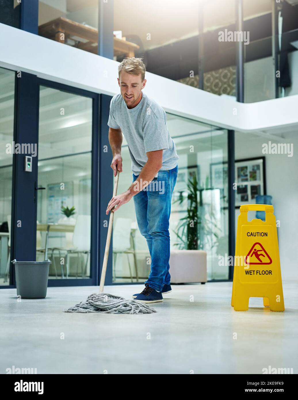 Caution Slippery when wet. a young man mopping the office floor Stock ...