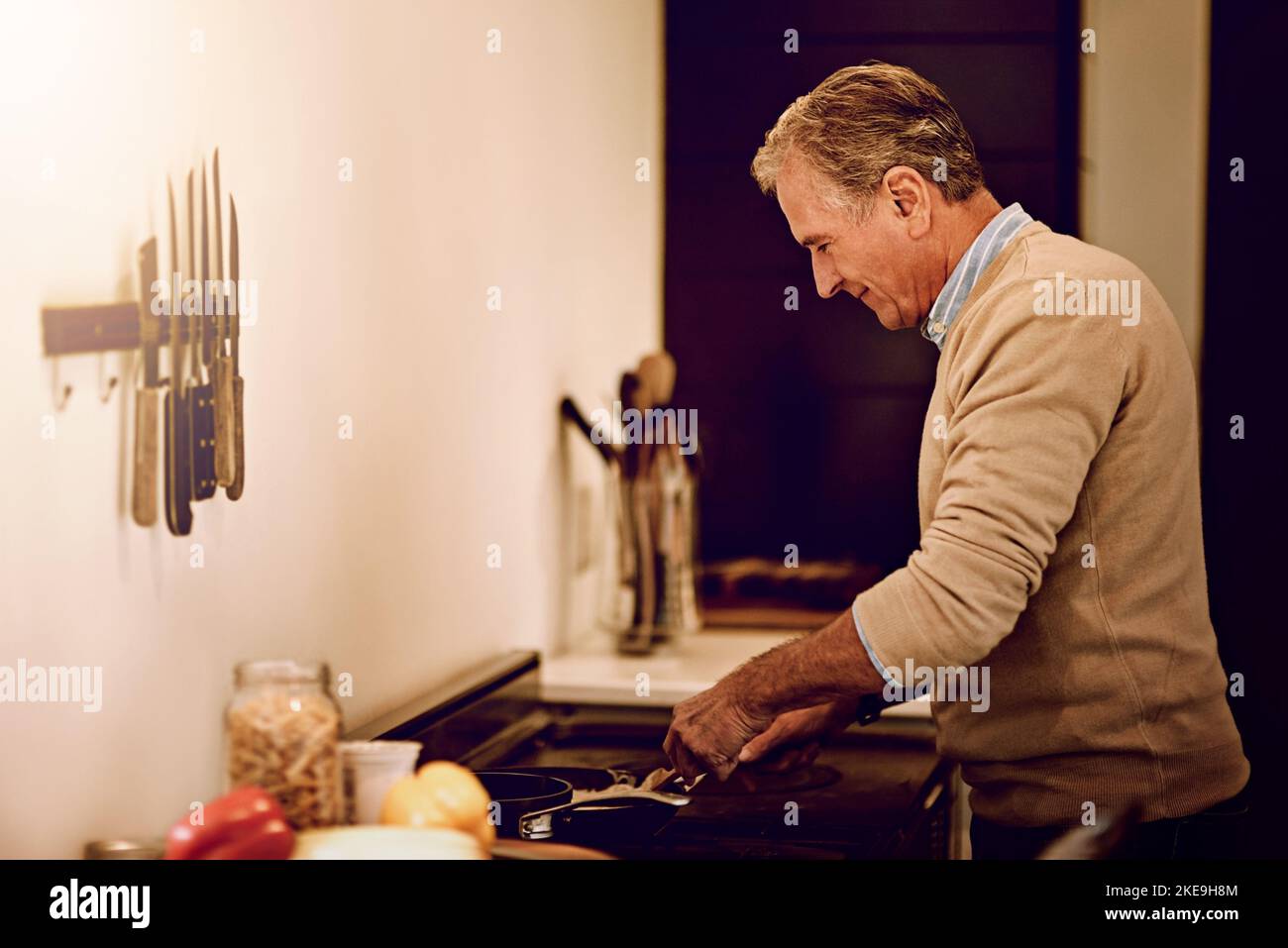 The kitchen is his happy place. an elderly man cooking a meal in his ...